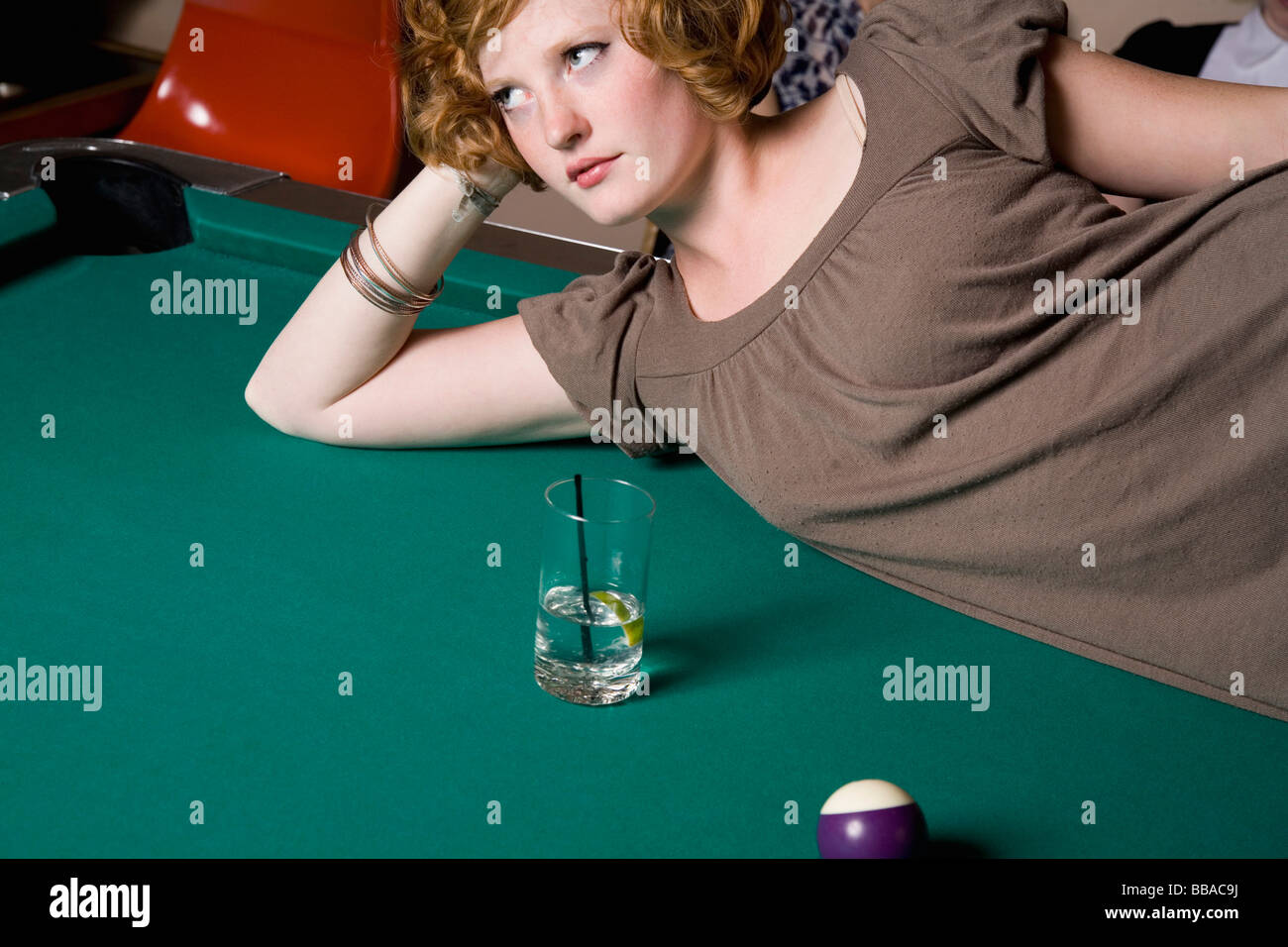 A young woman lying down across a pool table Stock Photo - Alamy