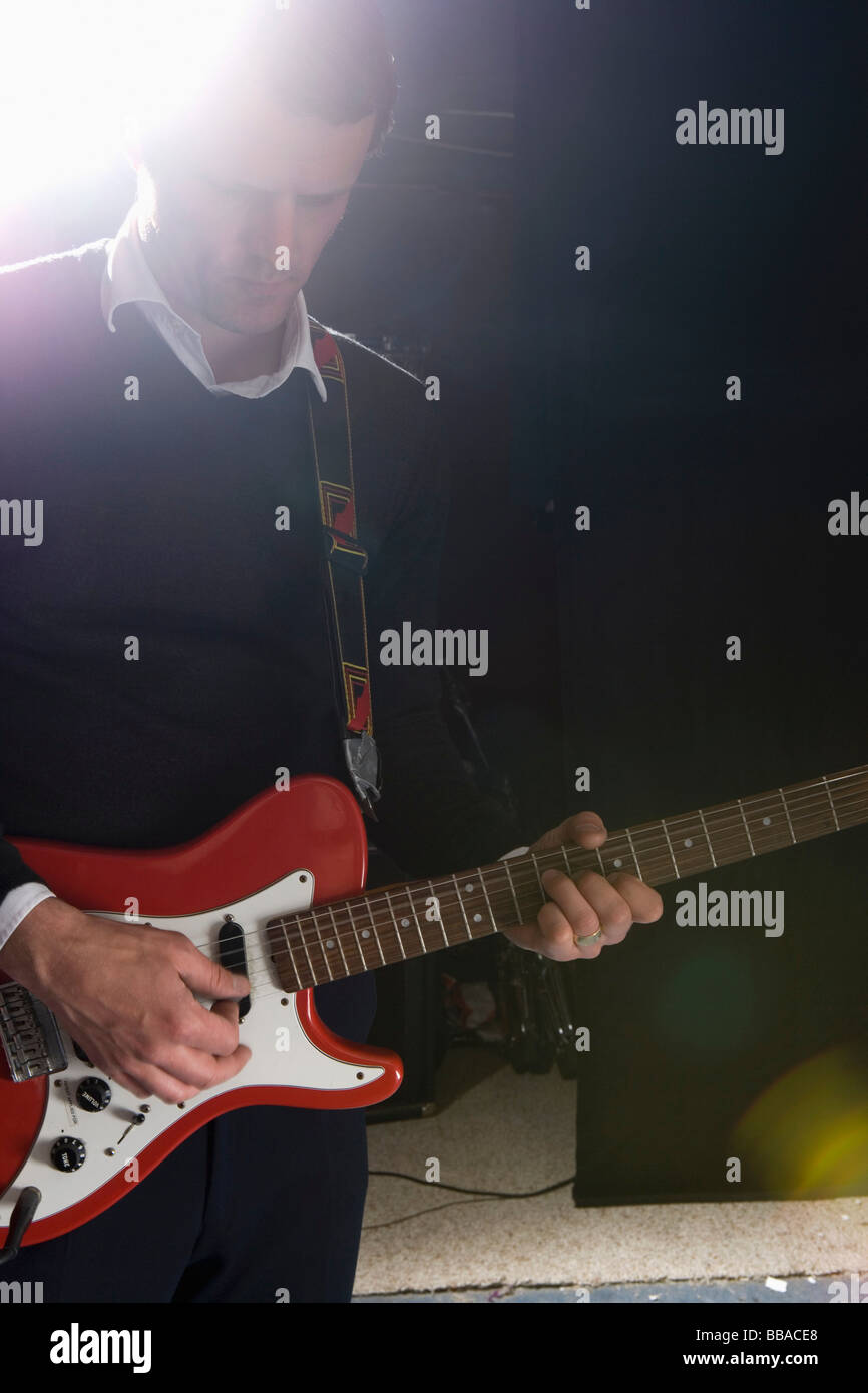 A man playing an electric guitar on stage Stock Photo - Alamy