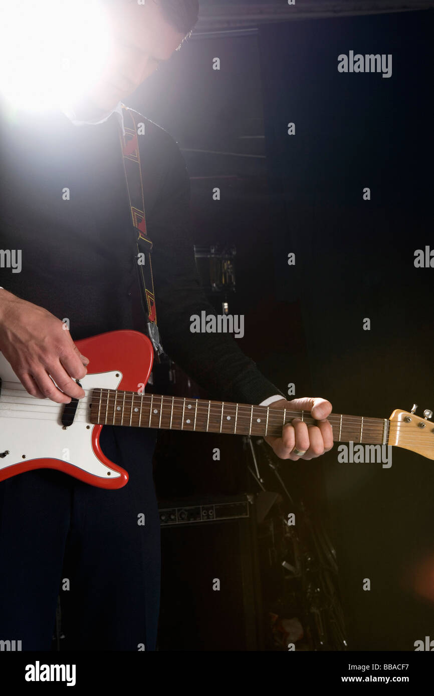 A man playing an electric guitar on stage Stock Photo - Alamy