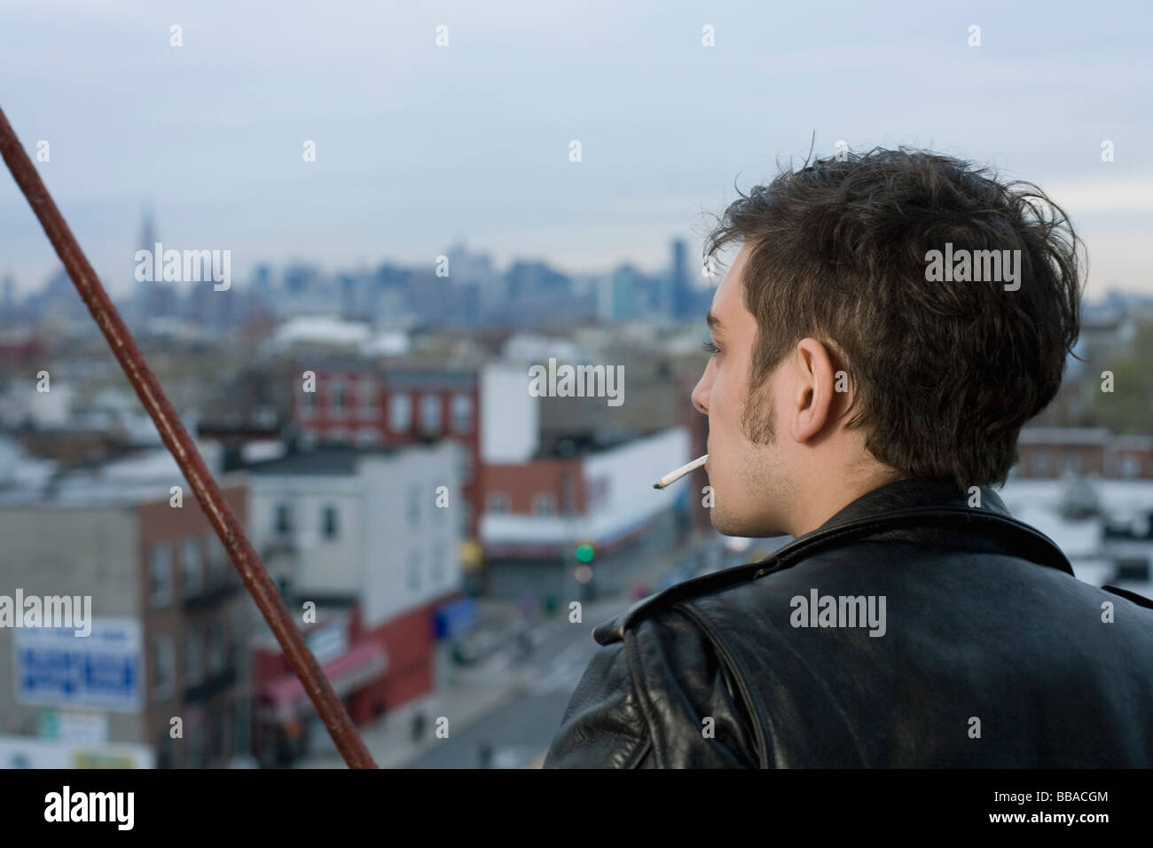 A young man smoking a cigarette on a fire escape Stock Photo - Alamy