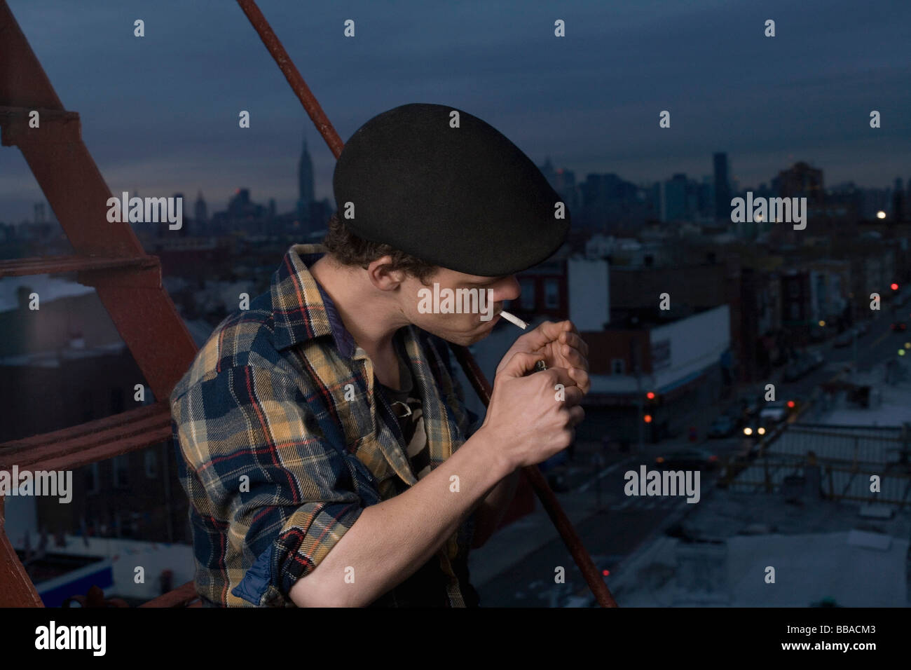A young man standing on a fire escape lighting a cigarette Stock Photo ...