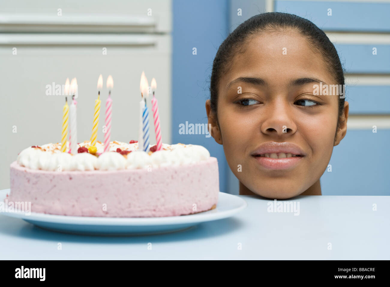 A young woman peeking at a birthday cake Stock Photo - Alamy