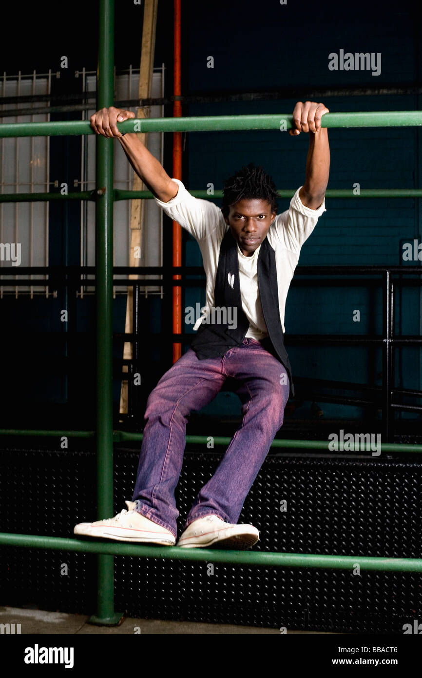 A young man holding onto a metal bar Stock Photo - Alamy