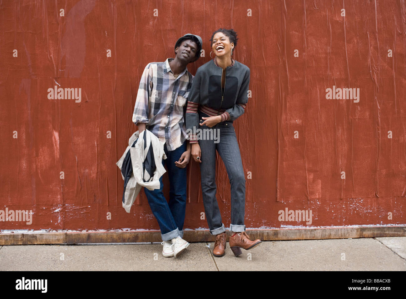 A young couple leaning against a wall Stock Photo - Alamy
