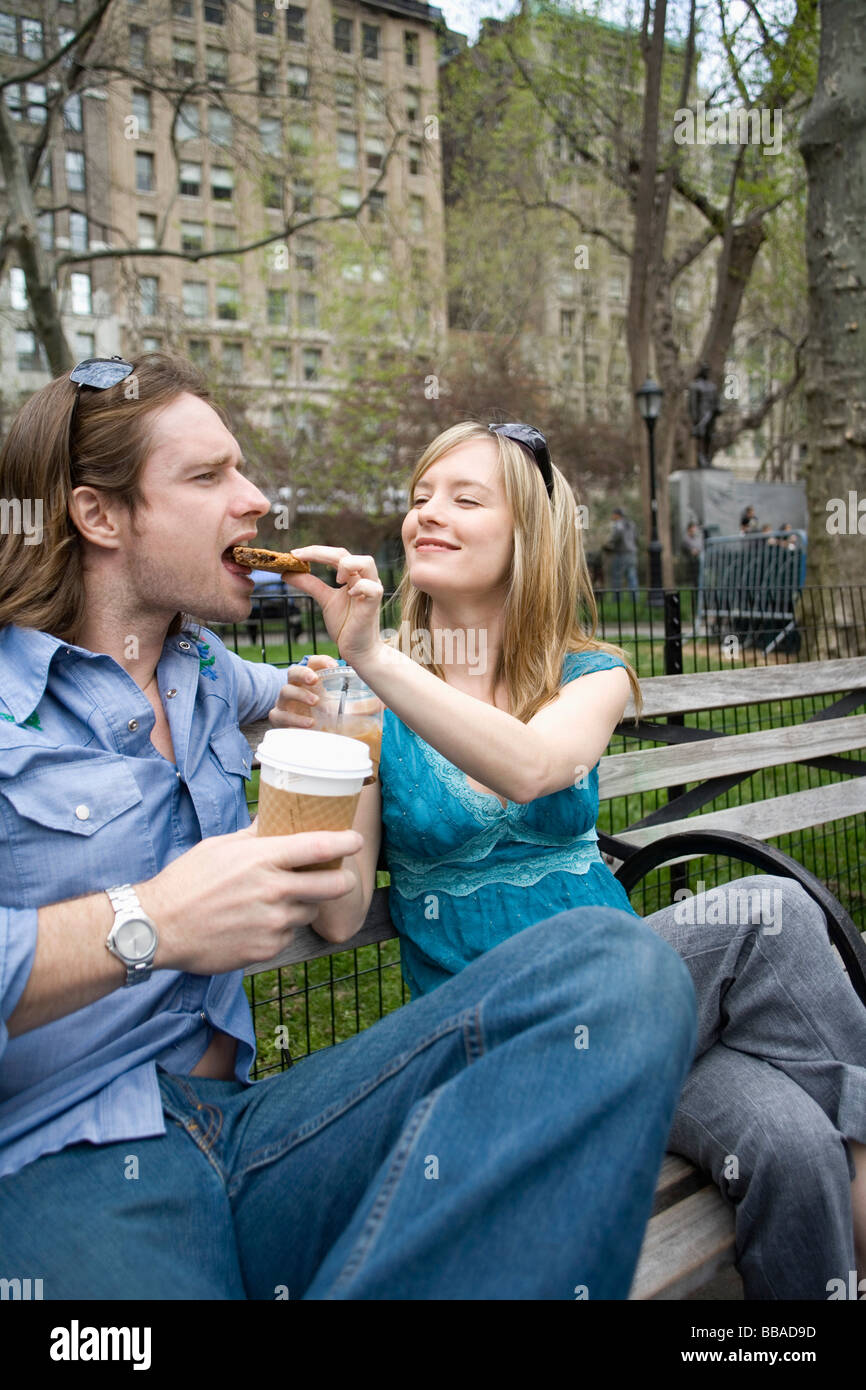 A woman feeding a man a cookie in a park, Central Park, New York City ...