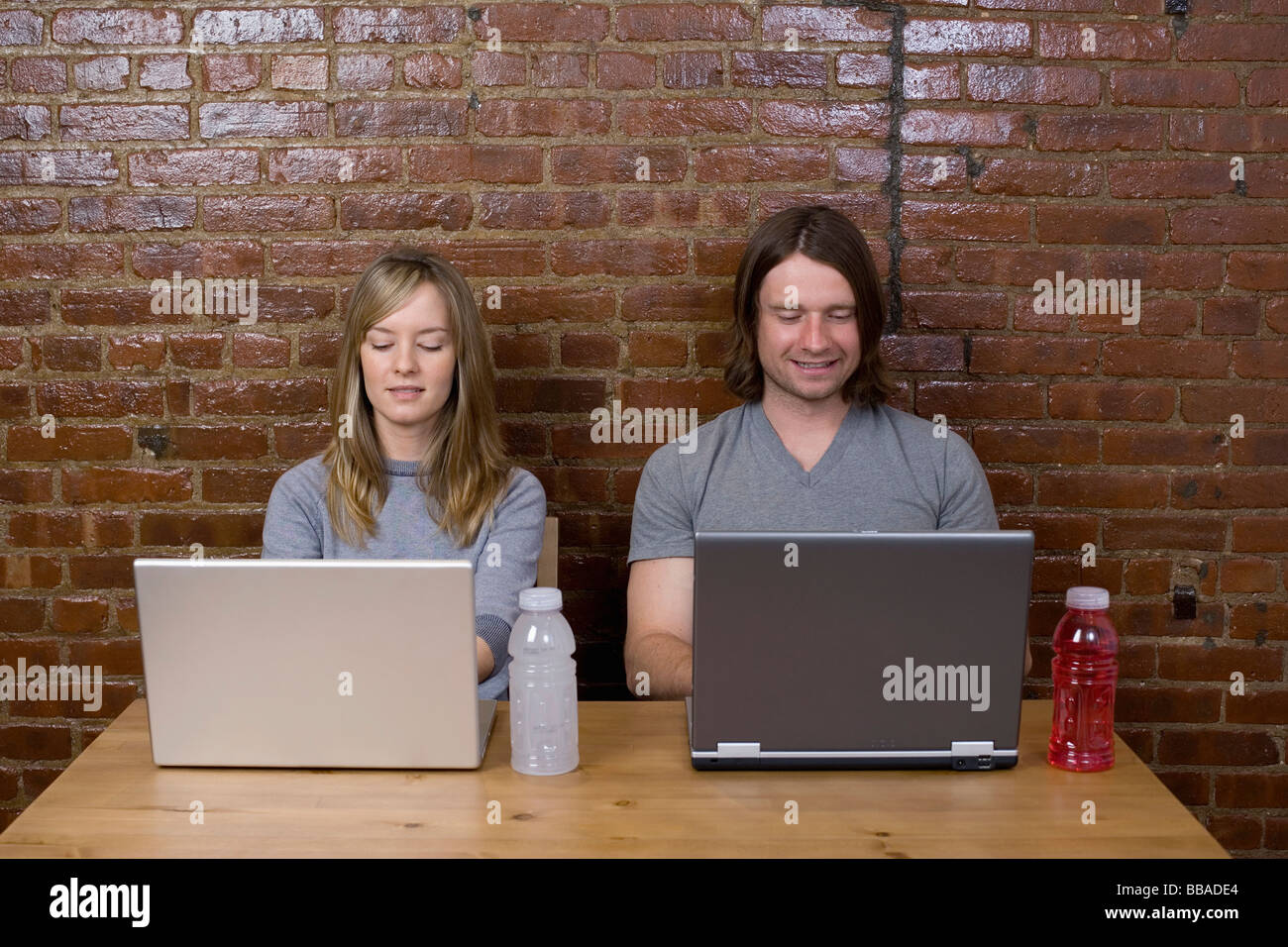 A young couple using laptops side by side Stock Photo - Alamy