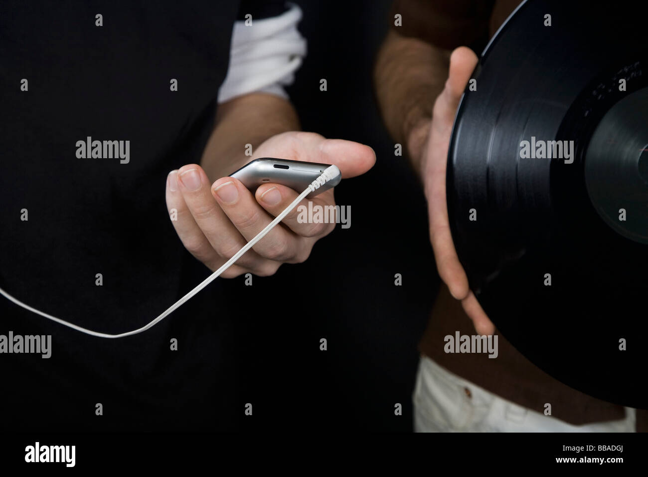 One man holding a MP3 player and another man holding a vinyl record ...