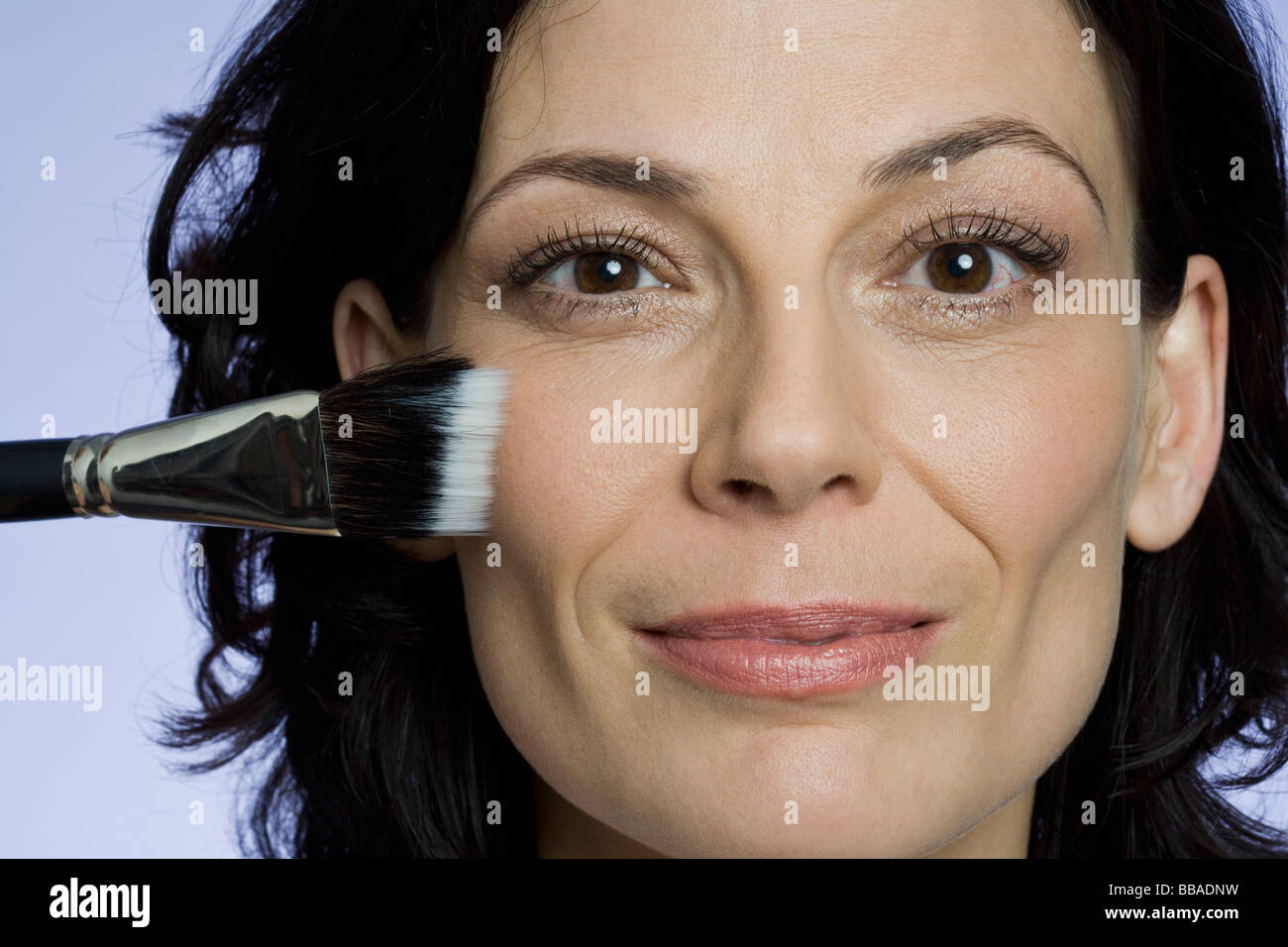 Headshot of a woman applying blusher Stock Photo - Alamy