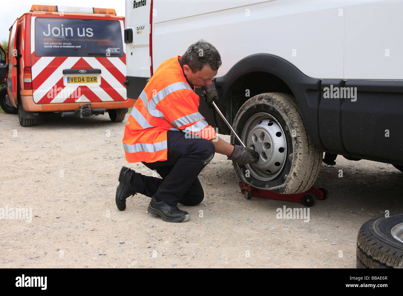 Breakdown recovery man changes the tyre on a white panel van Stock ...
