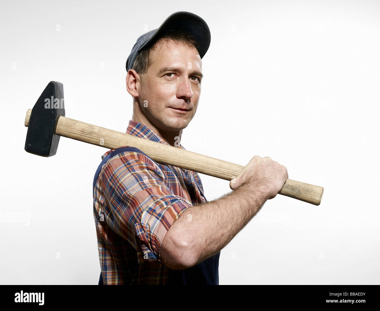 A man holding a sledgehammer over his shoulder Stock Photo - Alamy