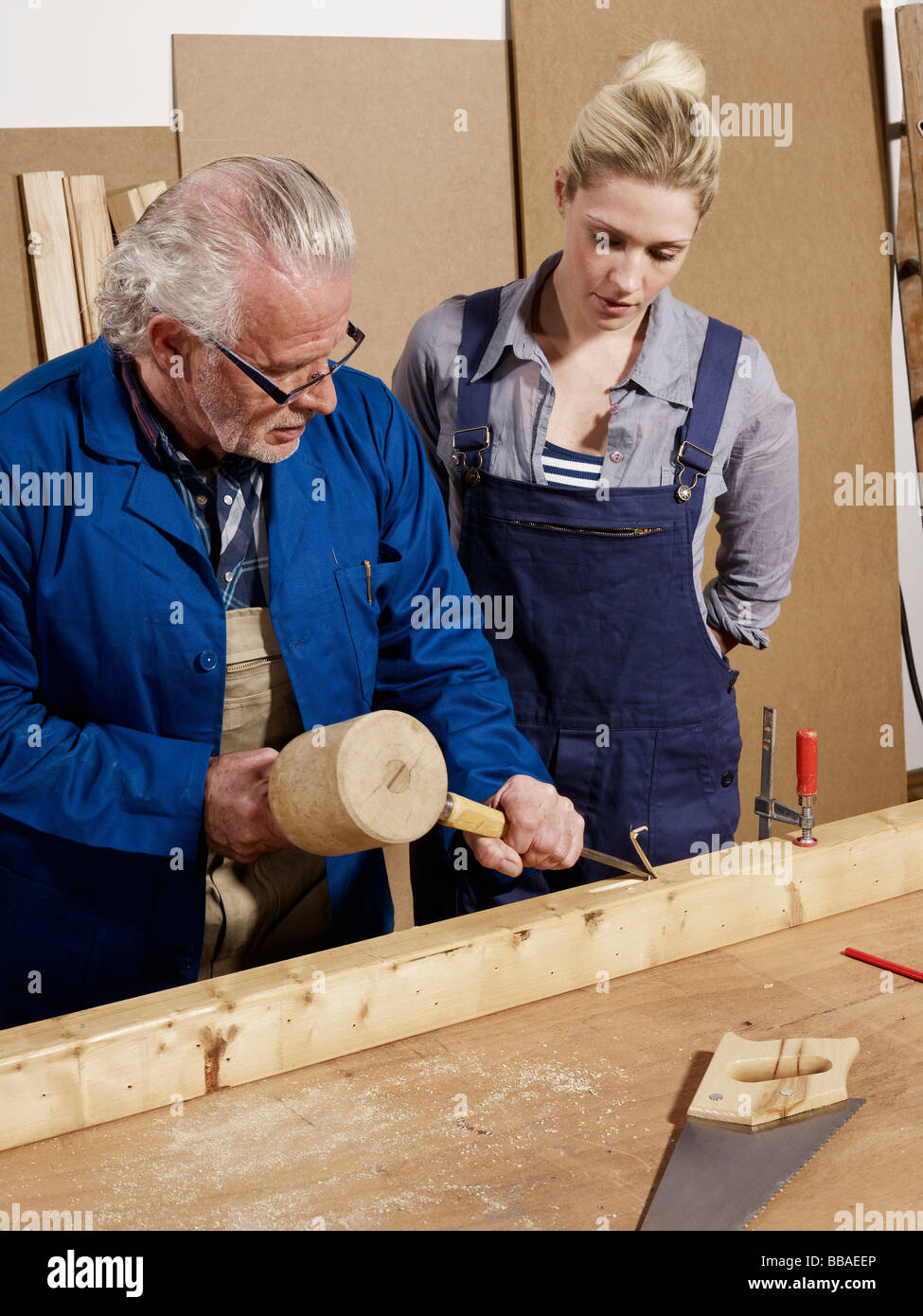 A man demonstrating wood chiseling to a woman in a workshop Stock Photo ...