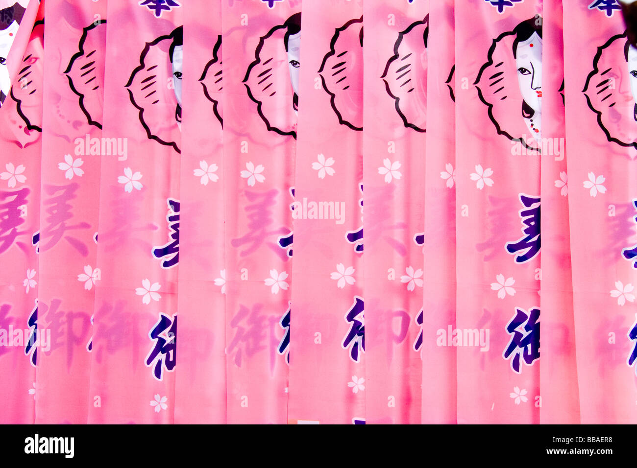 Row of Japanese pink banners with white stars, faces at the top ...