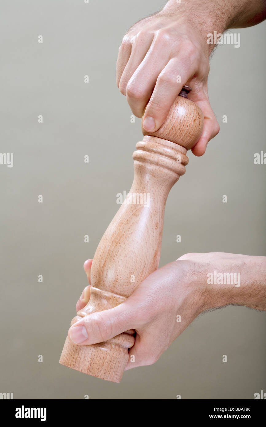 Two human hands using a pepper mill Stock Photo - Alamy