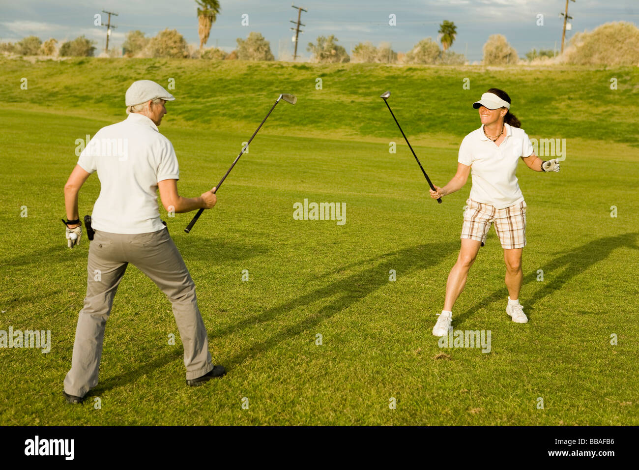 Two golfers sparring with golf clubs Stock Photo - Alamy