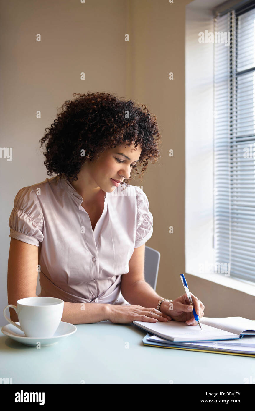 Woman by window writing in a book Stock Photo - Alamy