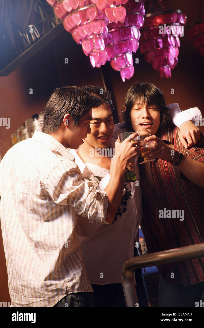 Three young men, toasting at entertainment club Stock Photo - Alamy