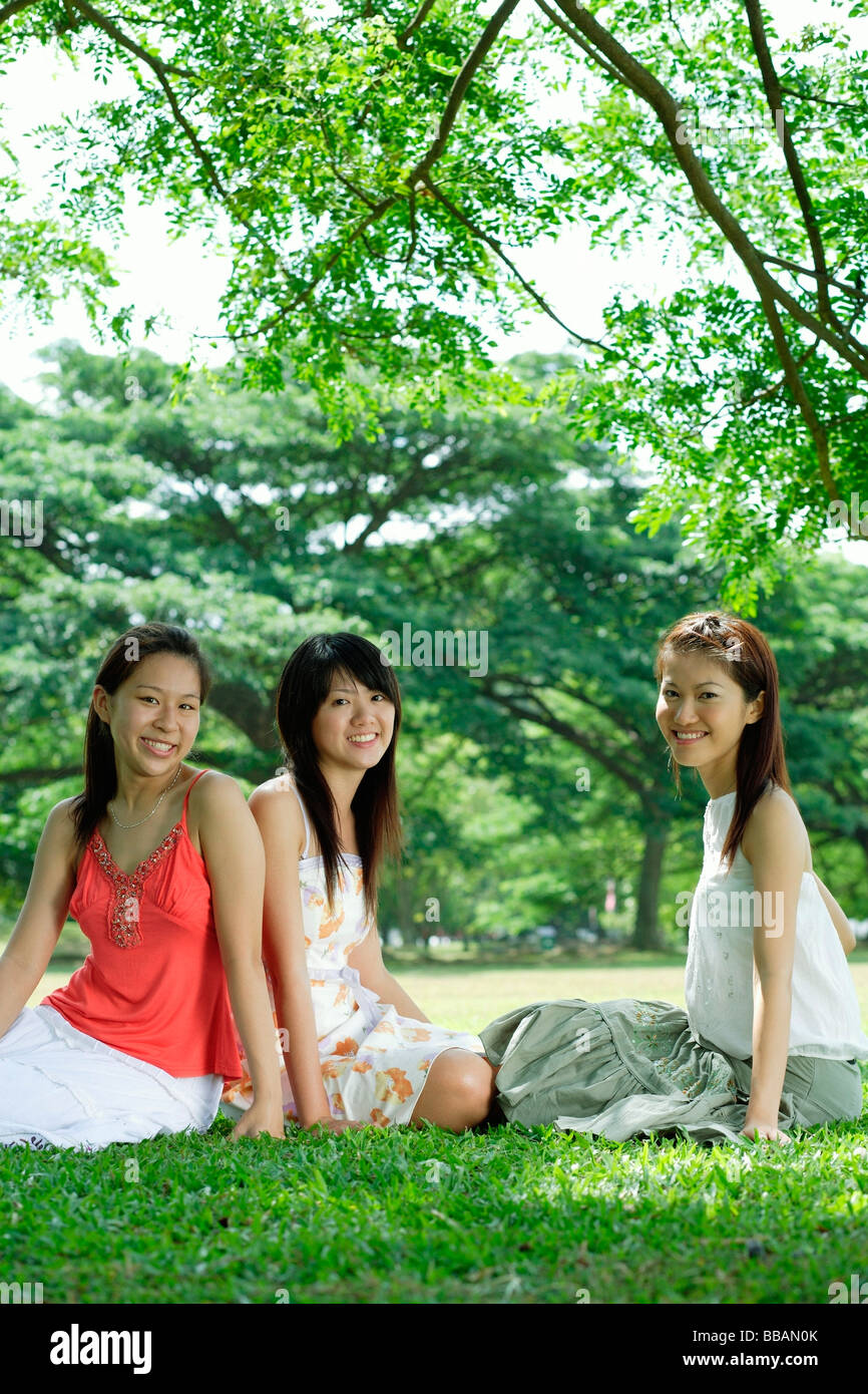 Young women sitting on grass, smiling at camera Stock Photo - Alamy