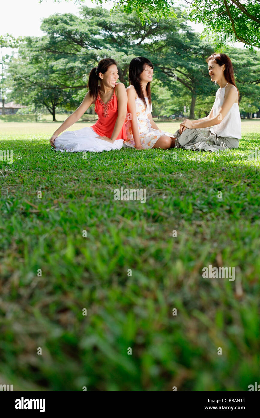 Three women sitting on grass in park Stock Photo - Alamy