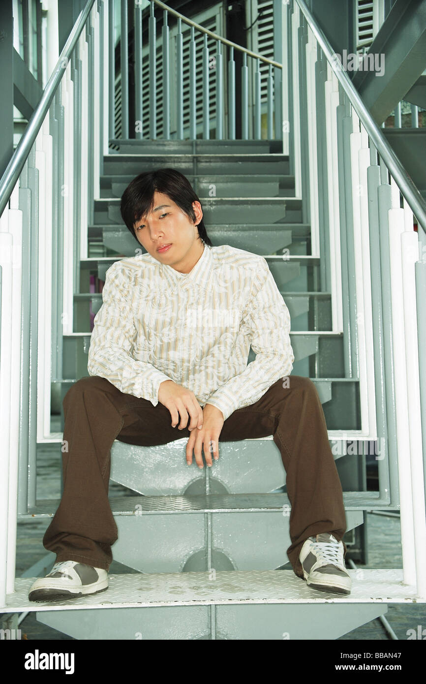 Young man sitting on steps, looking at camera Stock Photo - Alamy