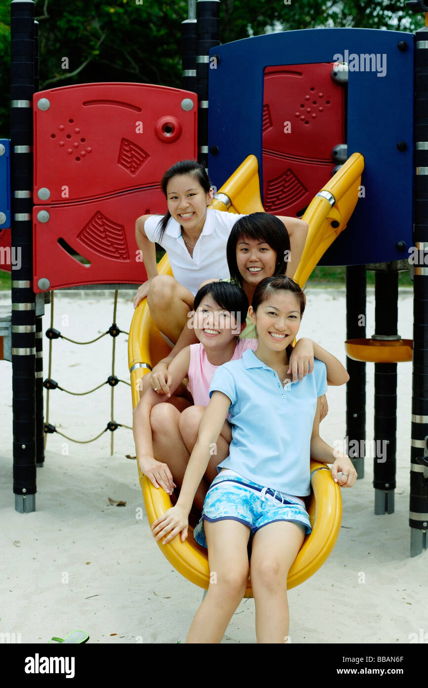 Young women sitting on slide, smiling at camera Stock Photo - Alamy