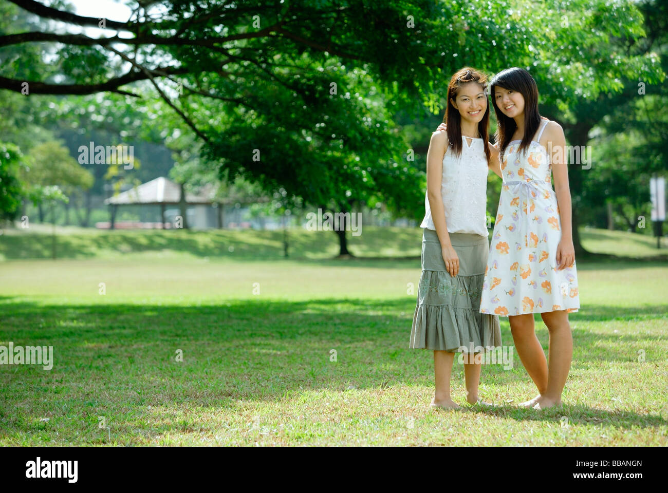 Two young women standing side by side, smiling at camera Stock Photo ...