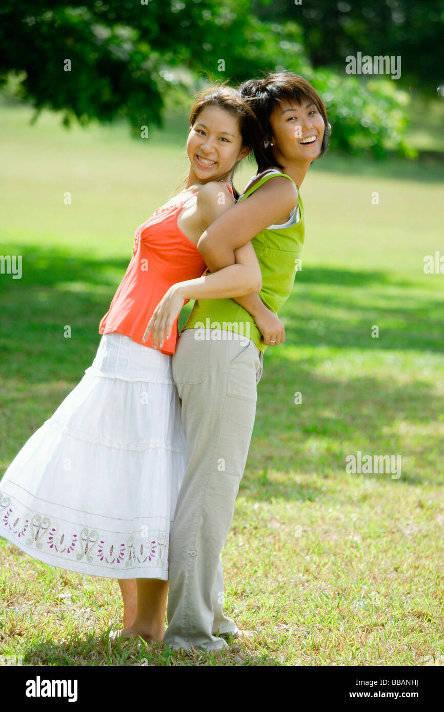 Two young women standing back to back, arm in arm Stock Photo - Alamy
