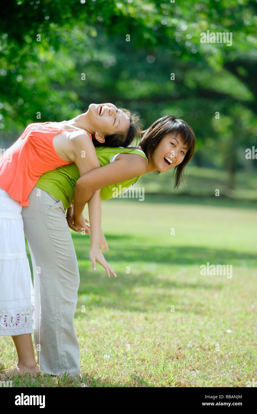 Two young women, back to back, one bending forward Stock Photo - Alamy