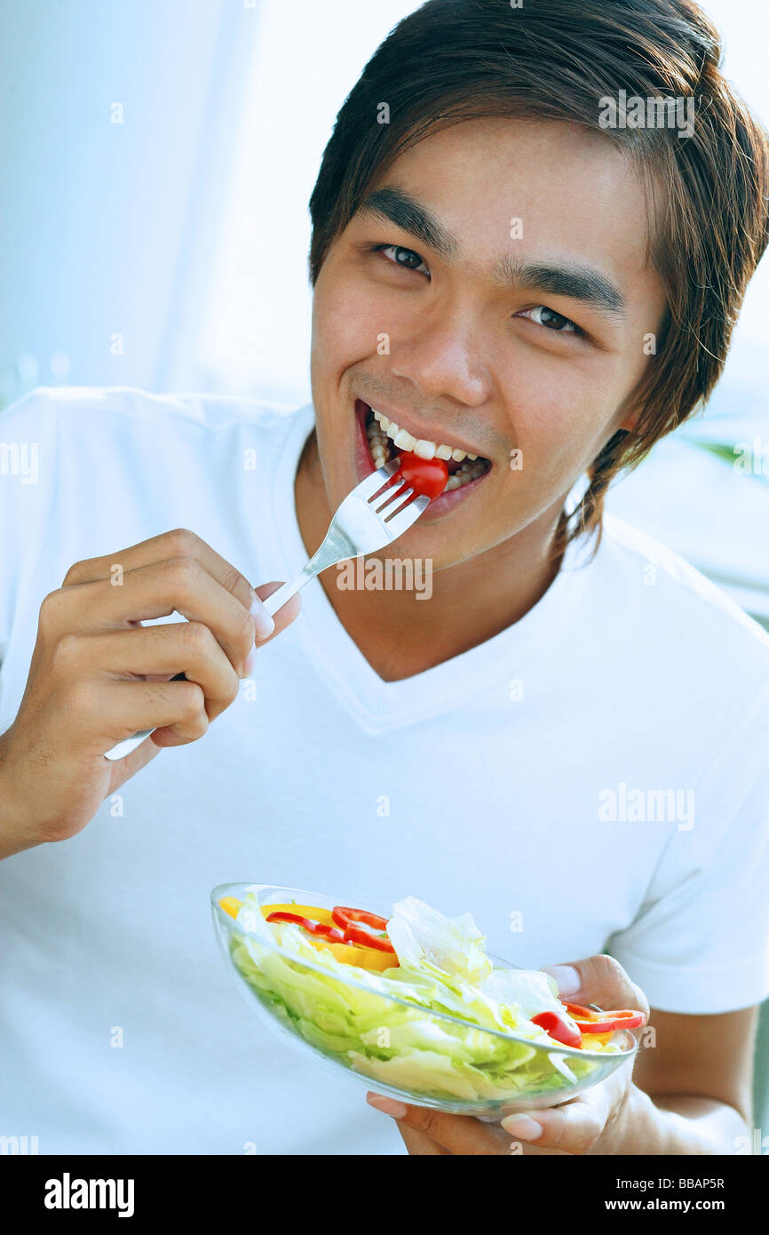 Young man looking at camera, eating salad Stock Photo - Alamy
