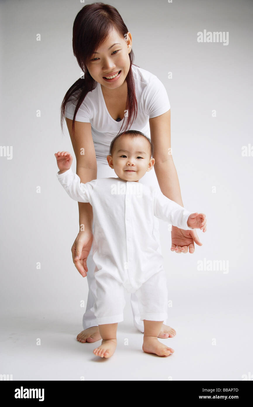 Baby girl standing, mother behind her, portrait Stock Photo - Alamy