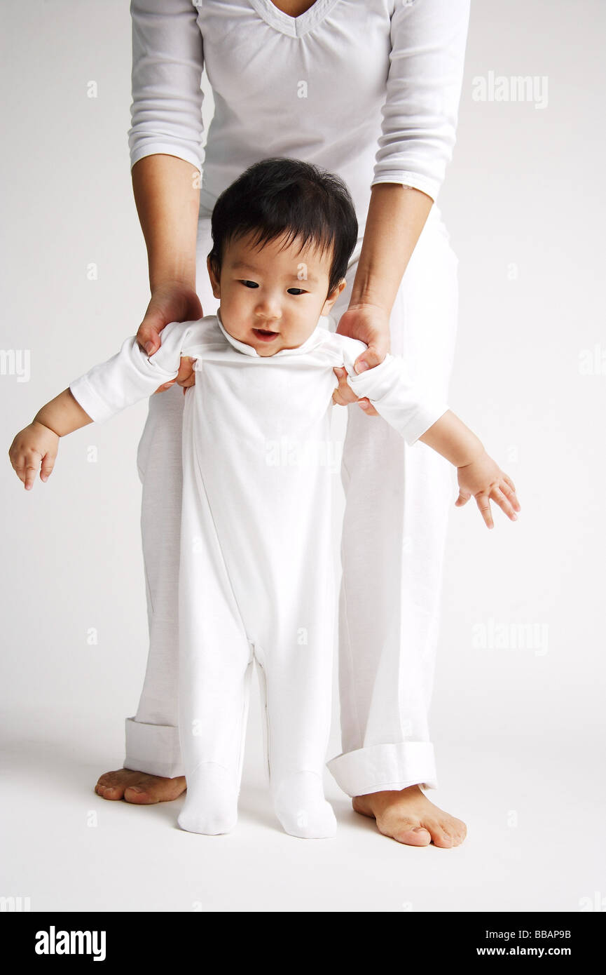 Baby boy standing, mother supporting him by holding his arms Stock ...