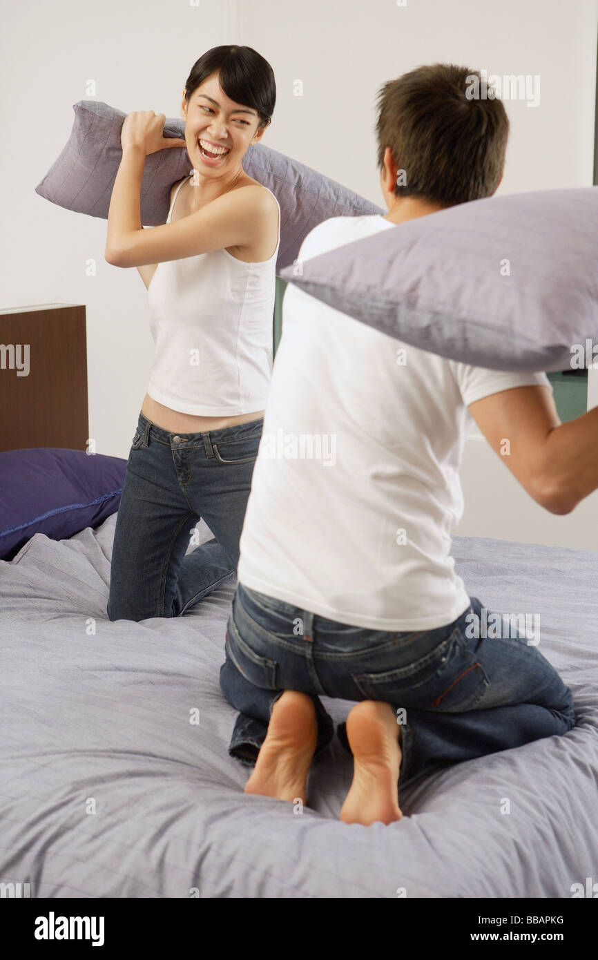 Couple having pillow fight in bedroom Stock Photo - Alamy