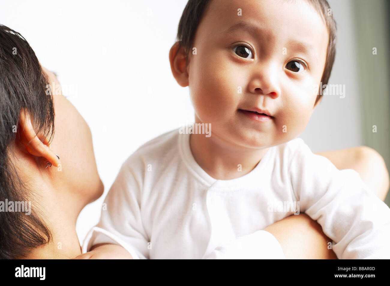 Mother carrying baby boy over her shoulder Stock Photo - Alamy