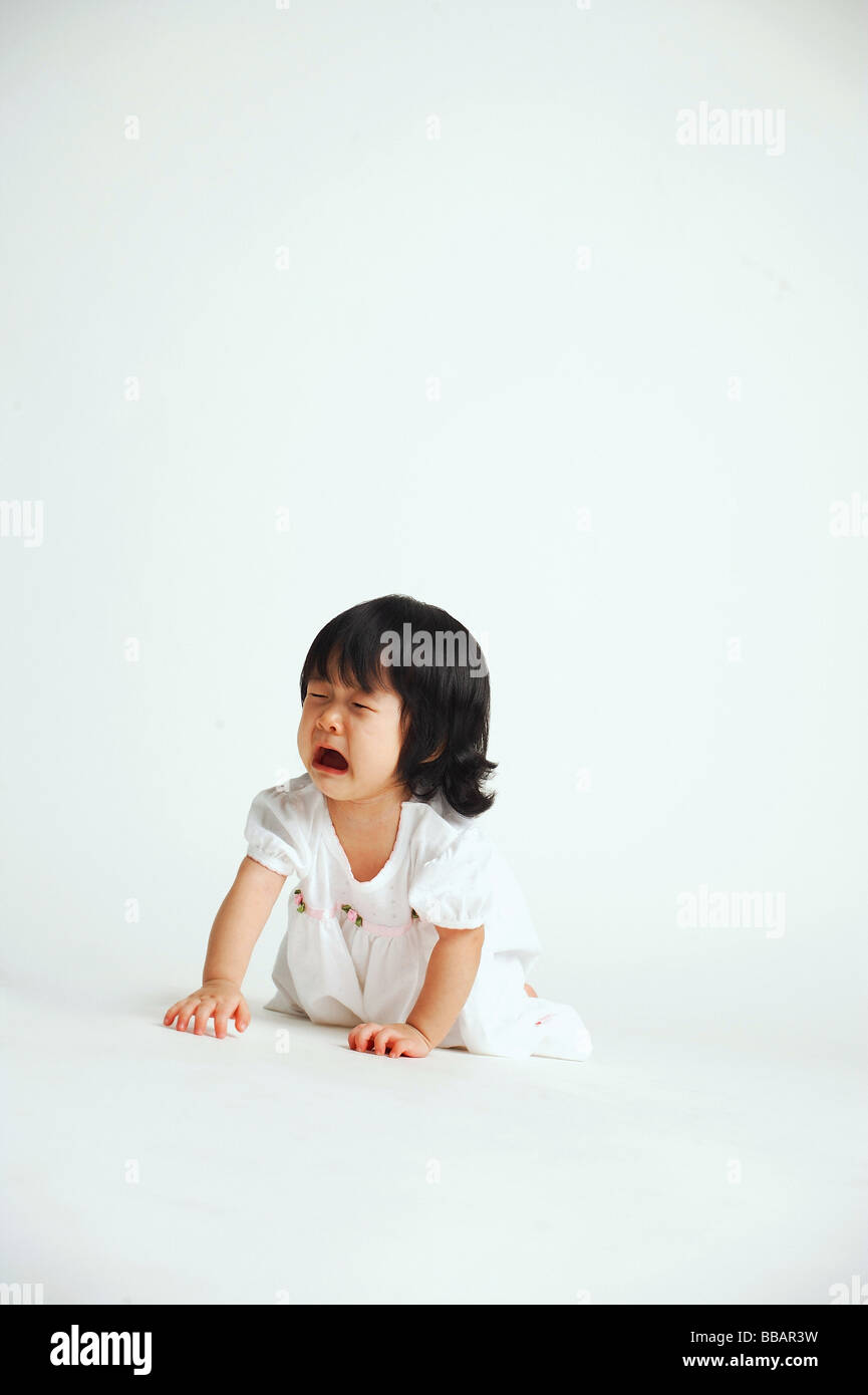 Baby girl crawling on floor, crying Stock Photo - Alamy