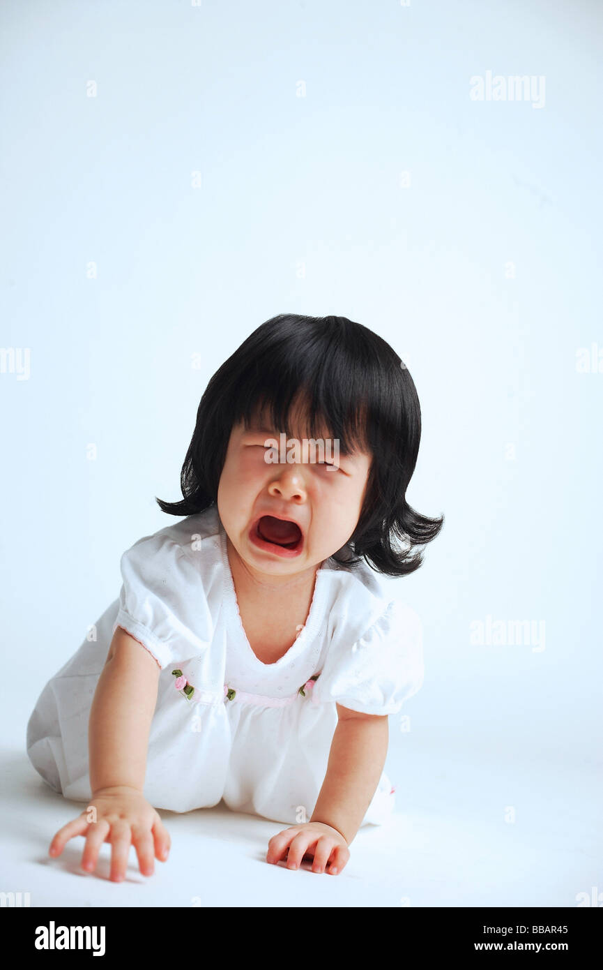 Baby girl crawling on floor, crying, mouth open Stock Photo - Alamy