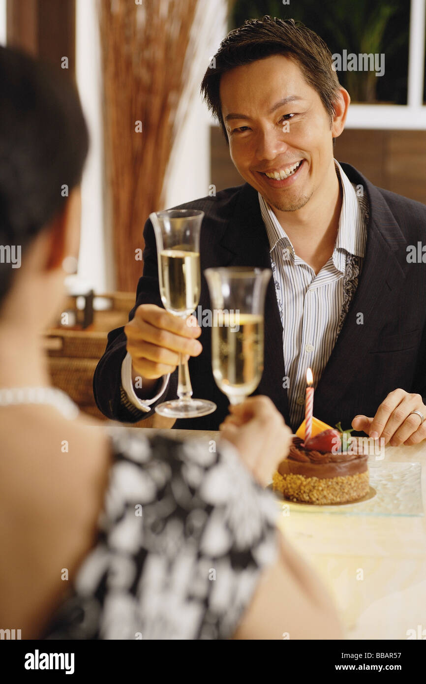 Couple at table, toasting with champagne, cake on table Stock Photo - Alamy