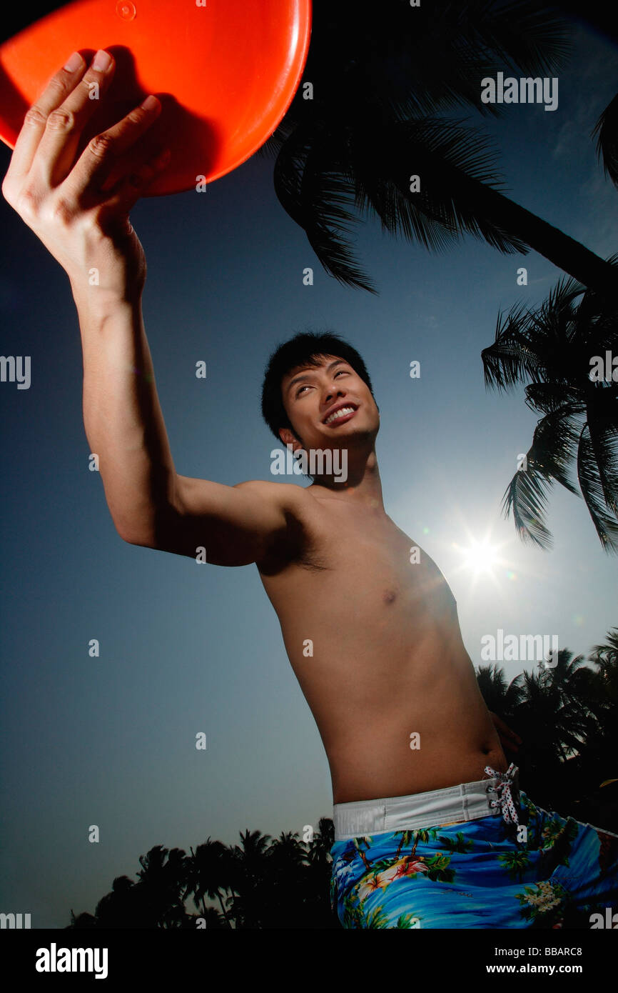 Young man on beach throwing Frisbee Stock Photo - Alamy