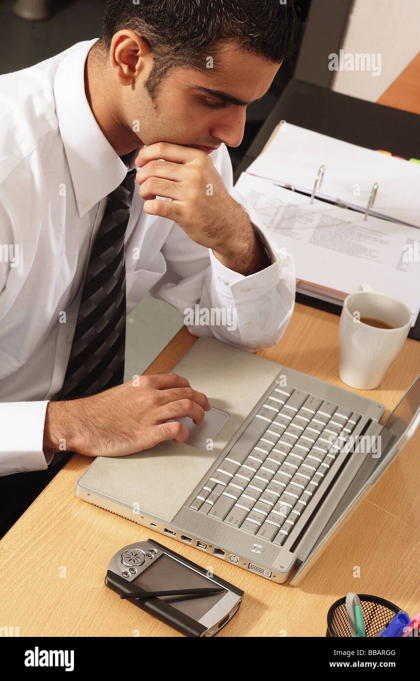 Executive sitting at desk, using laptop Stock Photo - Alamy