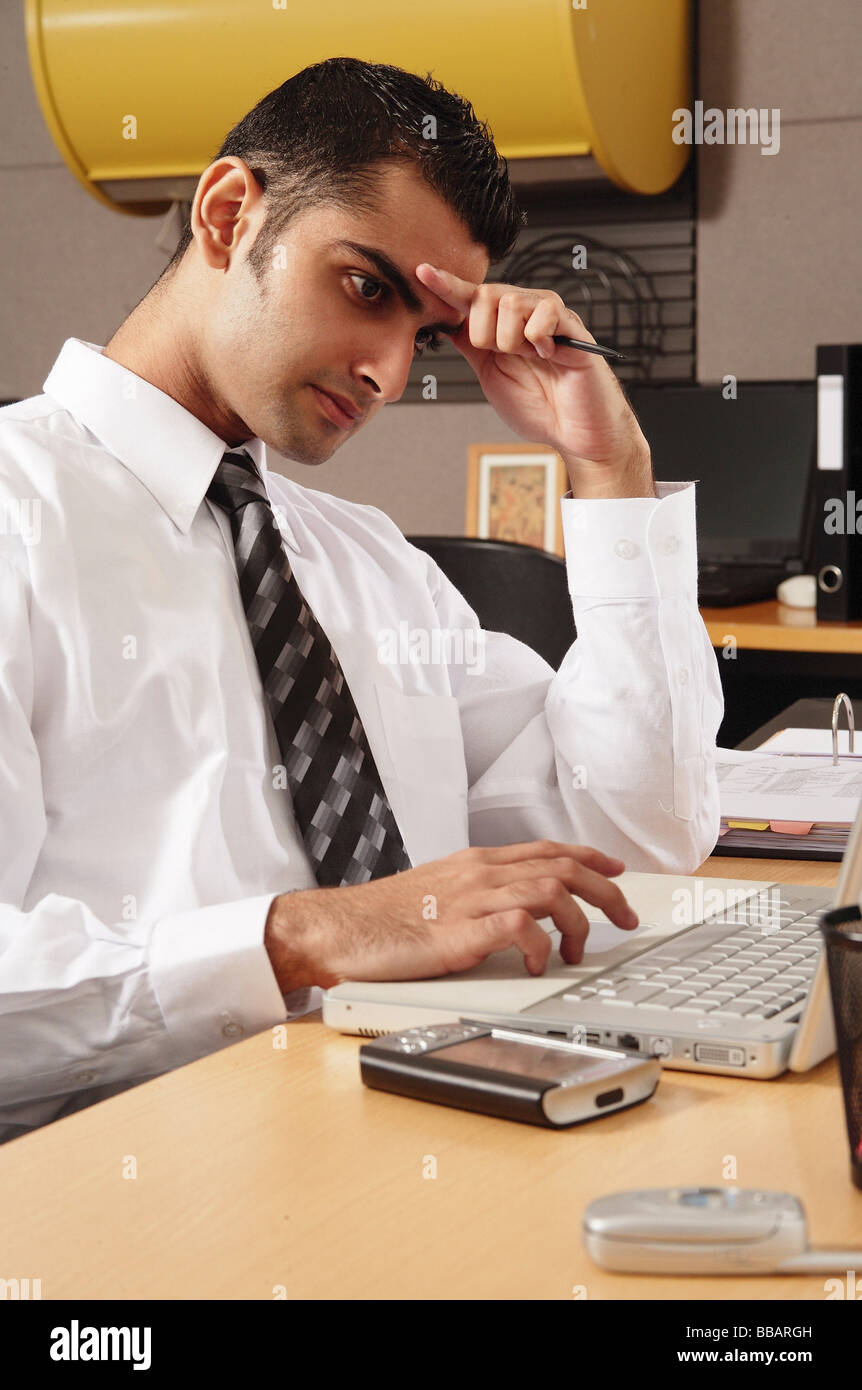 Executive sitting at desk, hand on head Stock Photo - Alamy