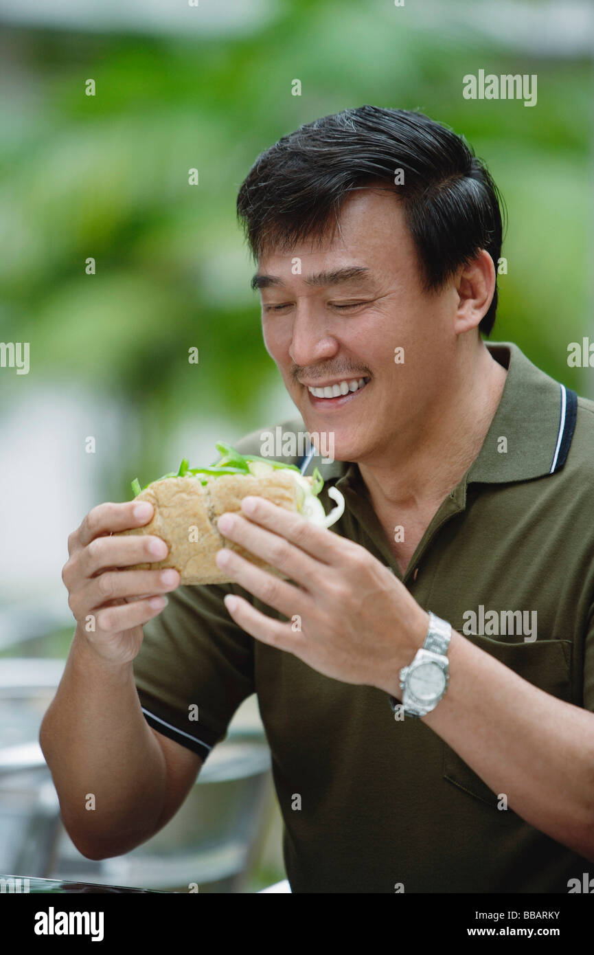 Man sitting in outdoor cafe eating sandwich Stock Photo - Alamy