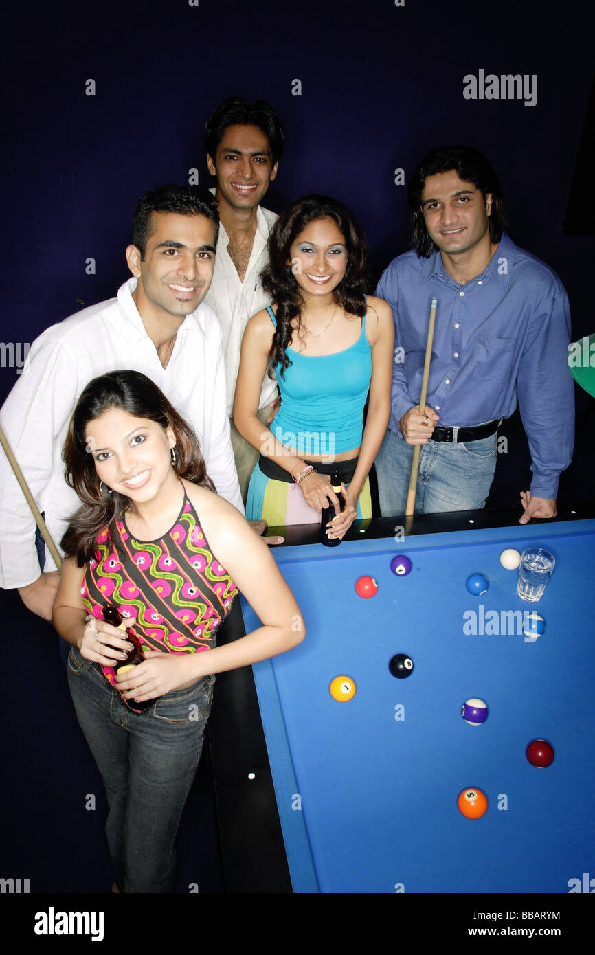 Young adults standing around pool table Stock Photo - Alamy