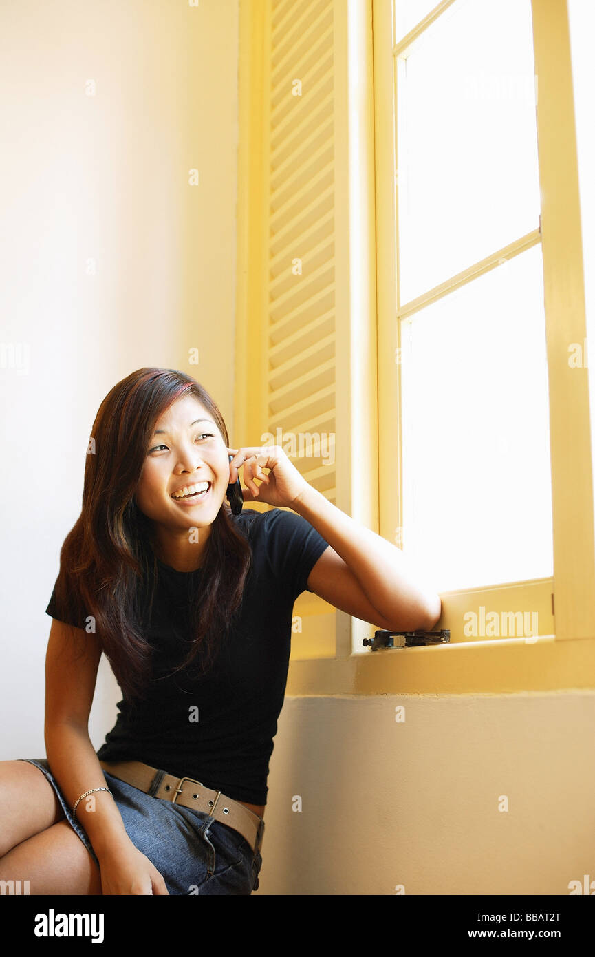 Young woman sitting, using mobile phone, portrait Stock Photo - Alamy