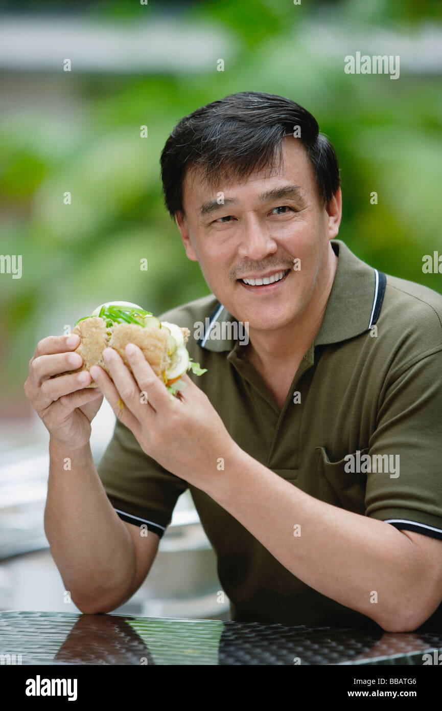 Man sitting outside eating a sandwich Stock Photo - Alamy