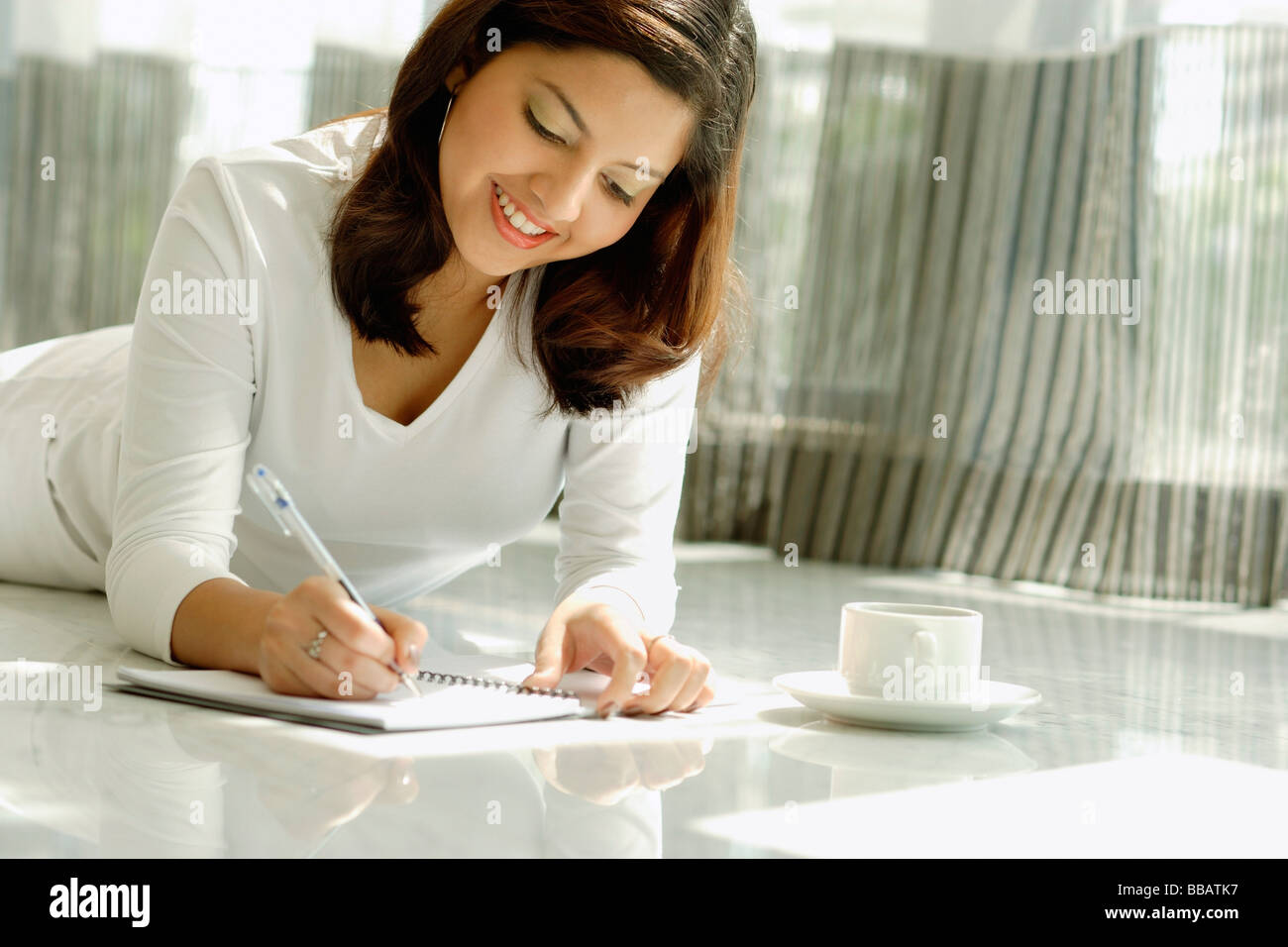 Woman writing in notebook, lying on floor Stock Photo - Alamy
