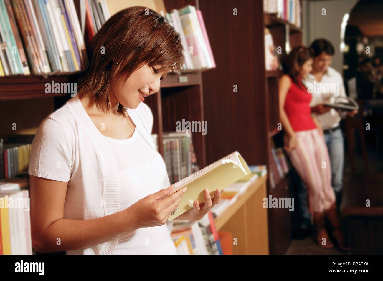 Young woman at bookstore, looking at book Stock Photo - Alamy