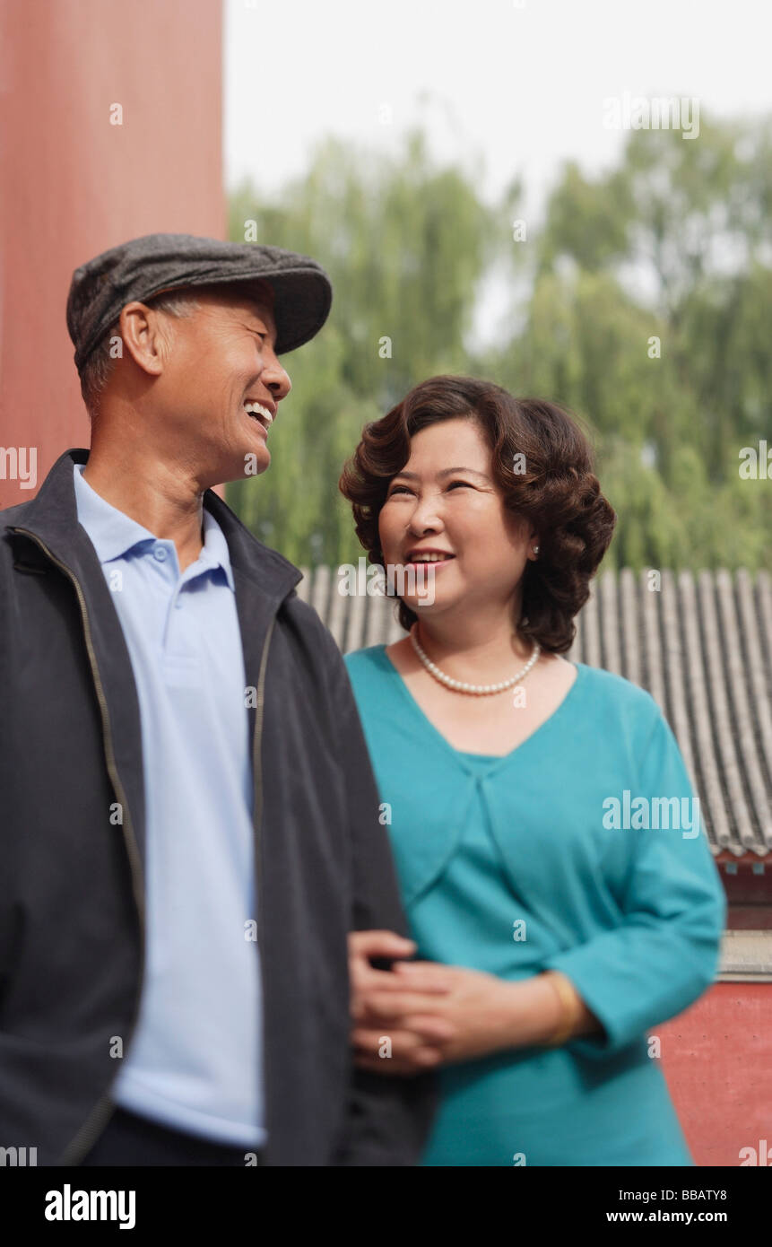A man and woman link arms as they walk together Stock Photo - Alamy