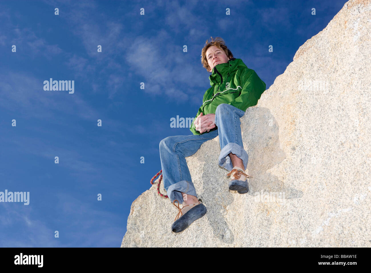 Climber sitting on mountain peak Stock Photo - Alamy