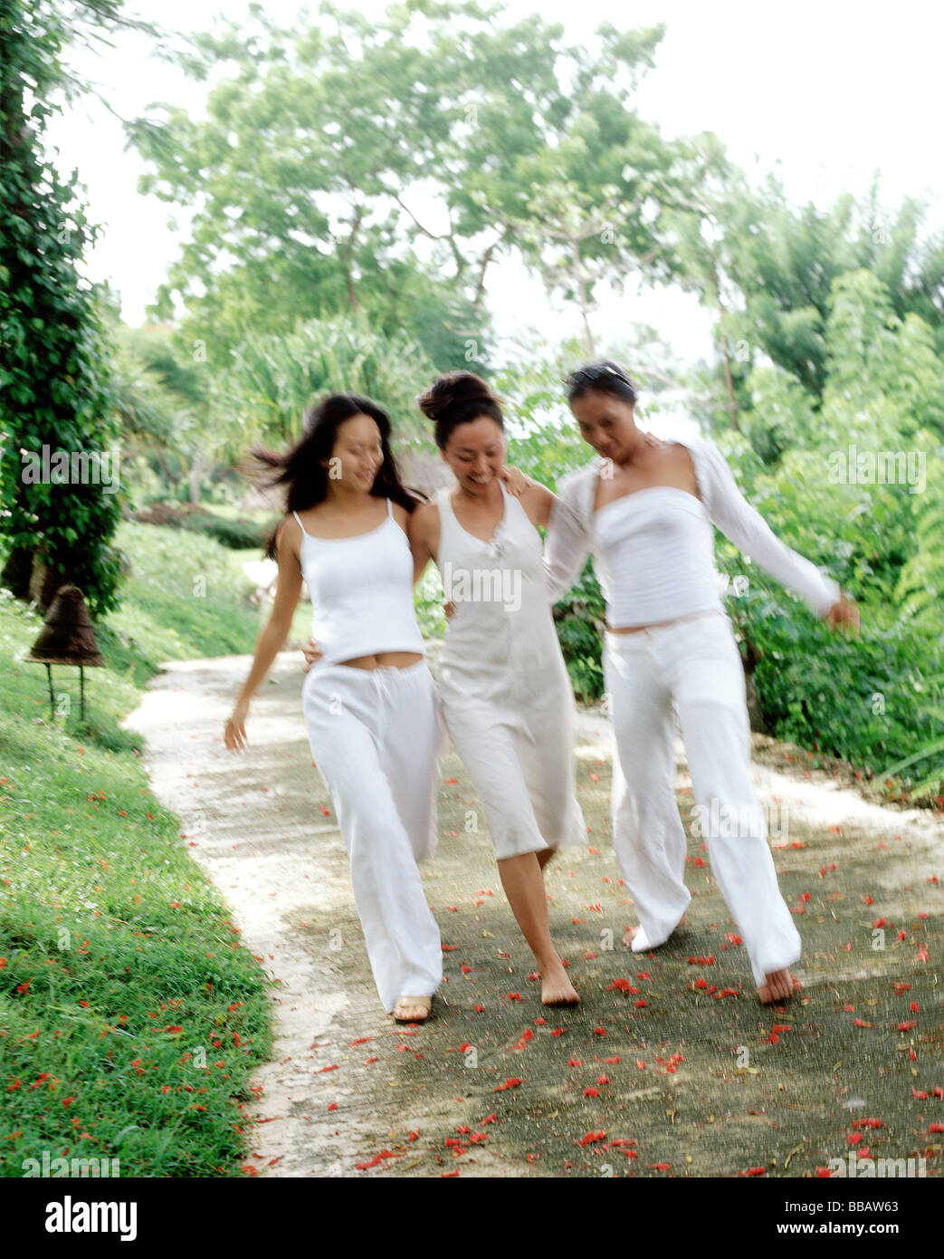 Three women wearing white strolling down path Stock Photo - Alamy