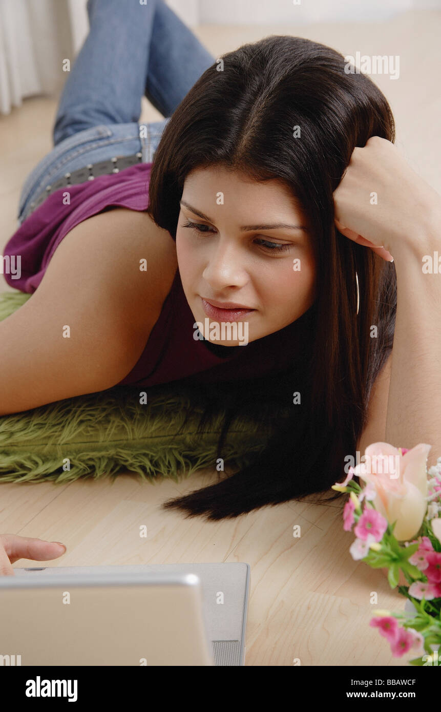 Young woman using laptop, lying on floor, leaning on hand Stock Photo ...