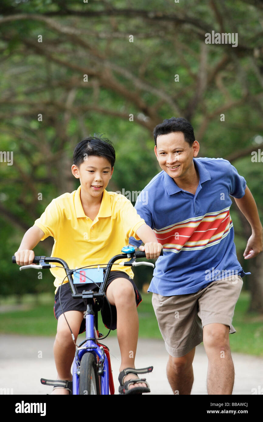 Boy on bicycle, father running behind him Stock Photo - Alamy
