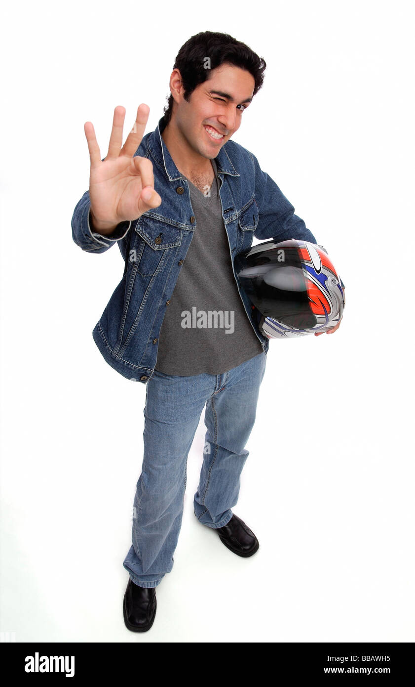Man carrying motorcycle helmet, looking up at camera, making hand sign ...